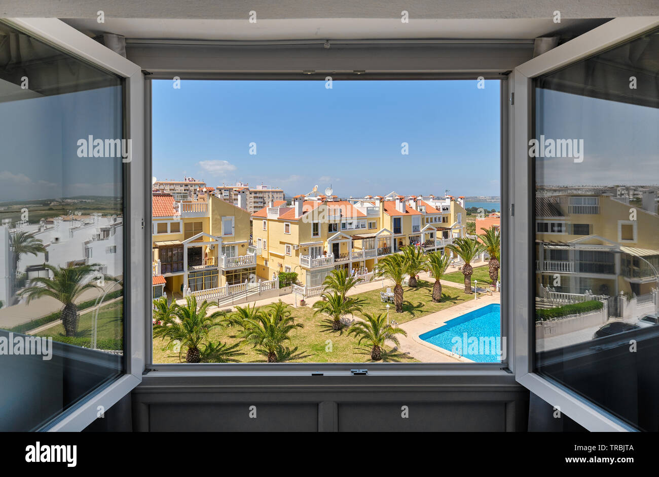 Through open window view to closed area of urbanization with planted ...