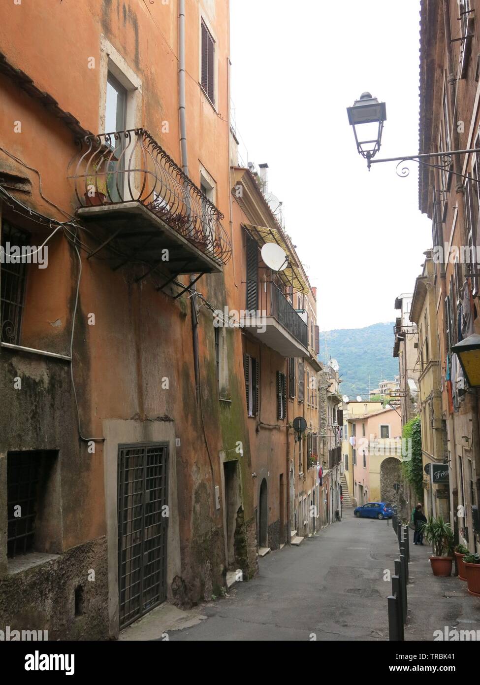 A typical narrow Italian street with tall buildings on either side ...
