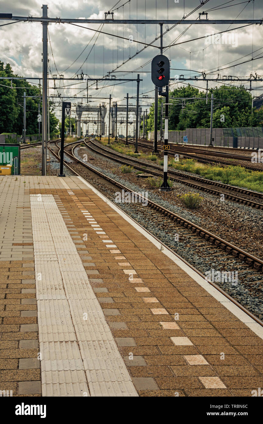 Platform, railroad rails and sign at train station under blue cloudy ...