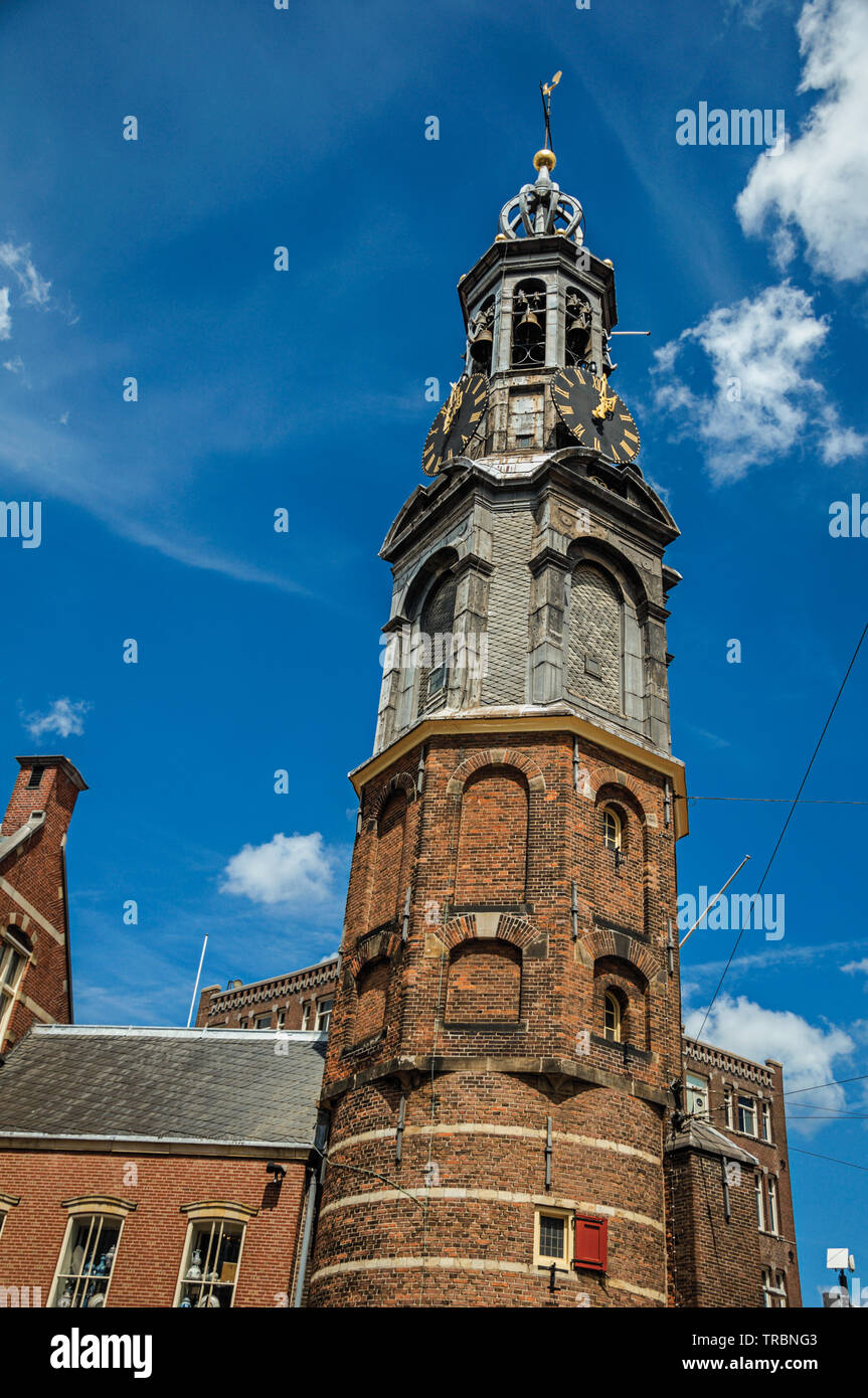 Steeple roof in a brick building with golden clock and blue sky in ...