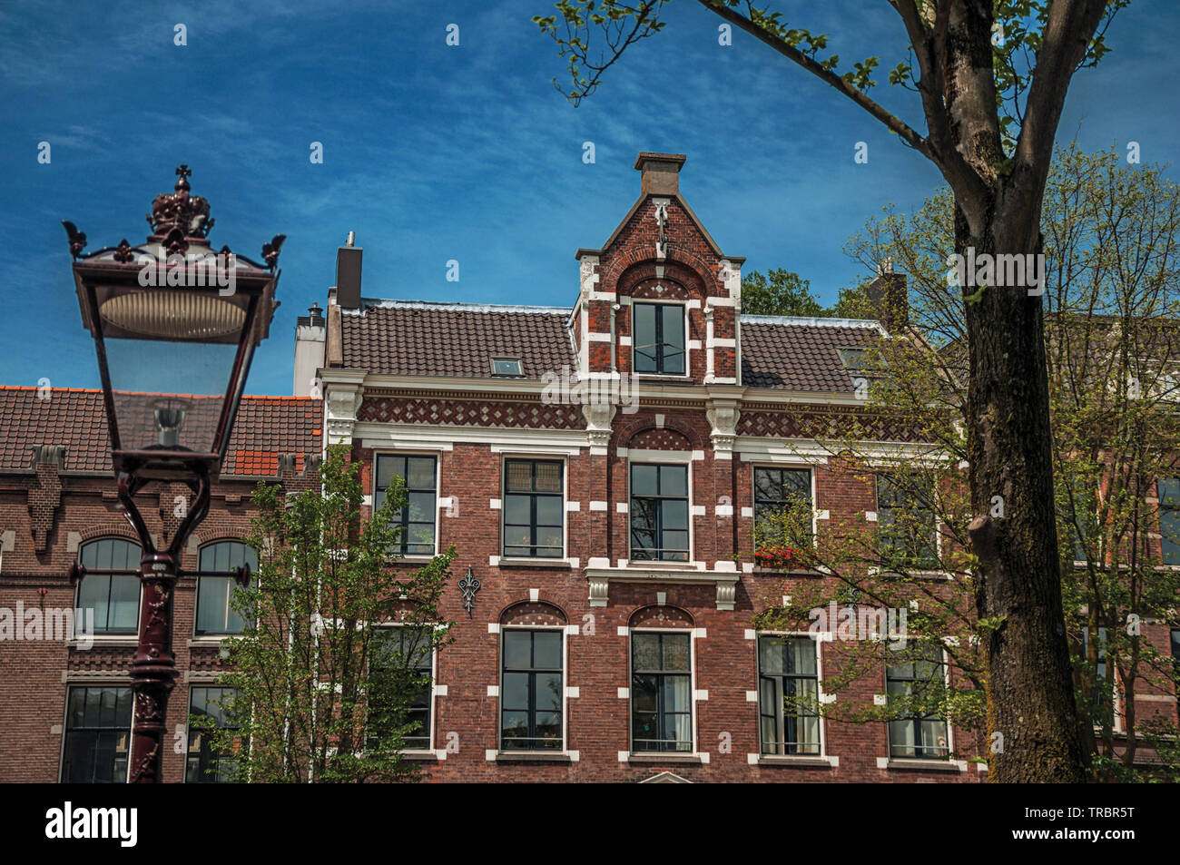 Light post, windows in old brick building facade and sunny blue sky in ...