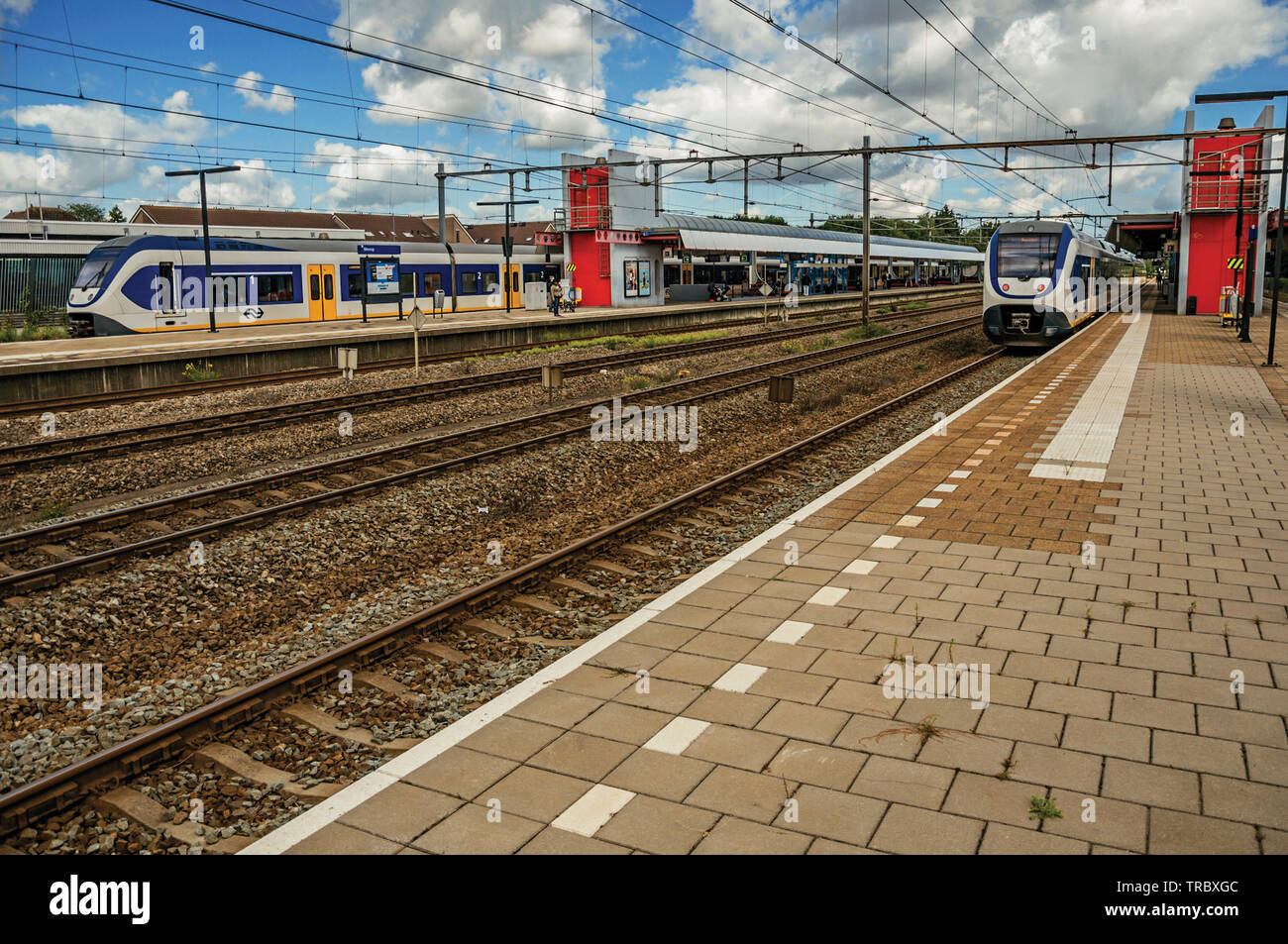 Locomotives stop on train station platforms, railroad rails and cloudy ...