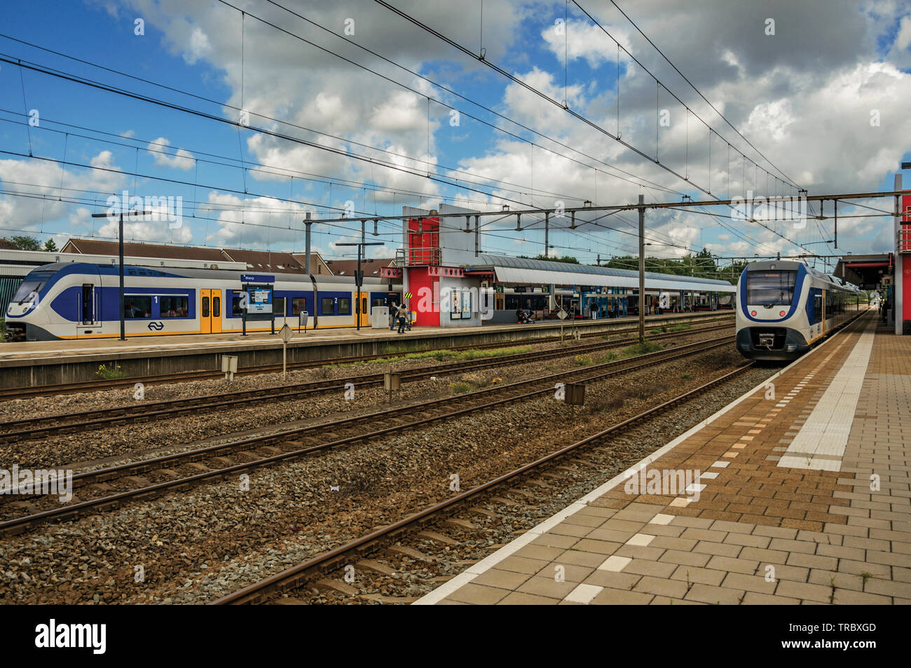 Locomotives stop on train station platforms, railroad rails and cloudy ...