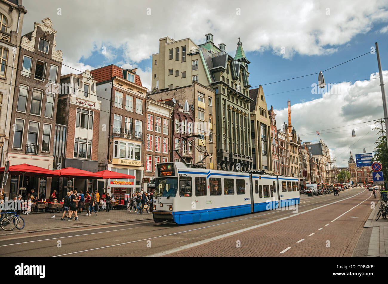 Street with tram, buildings and lots of people strolling in Amsterdam ...