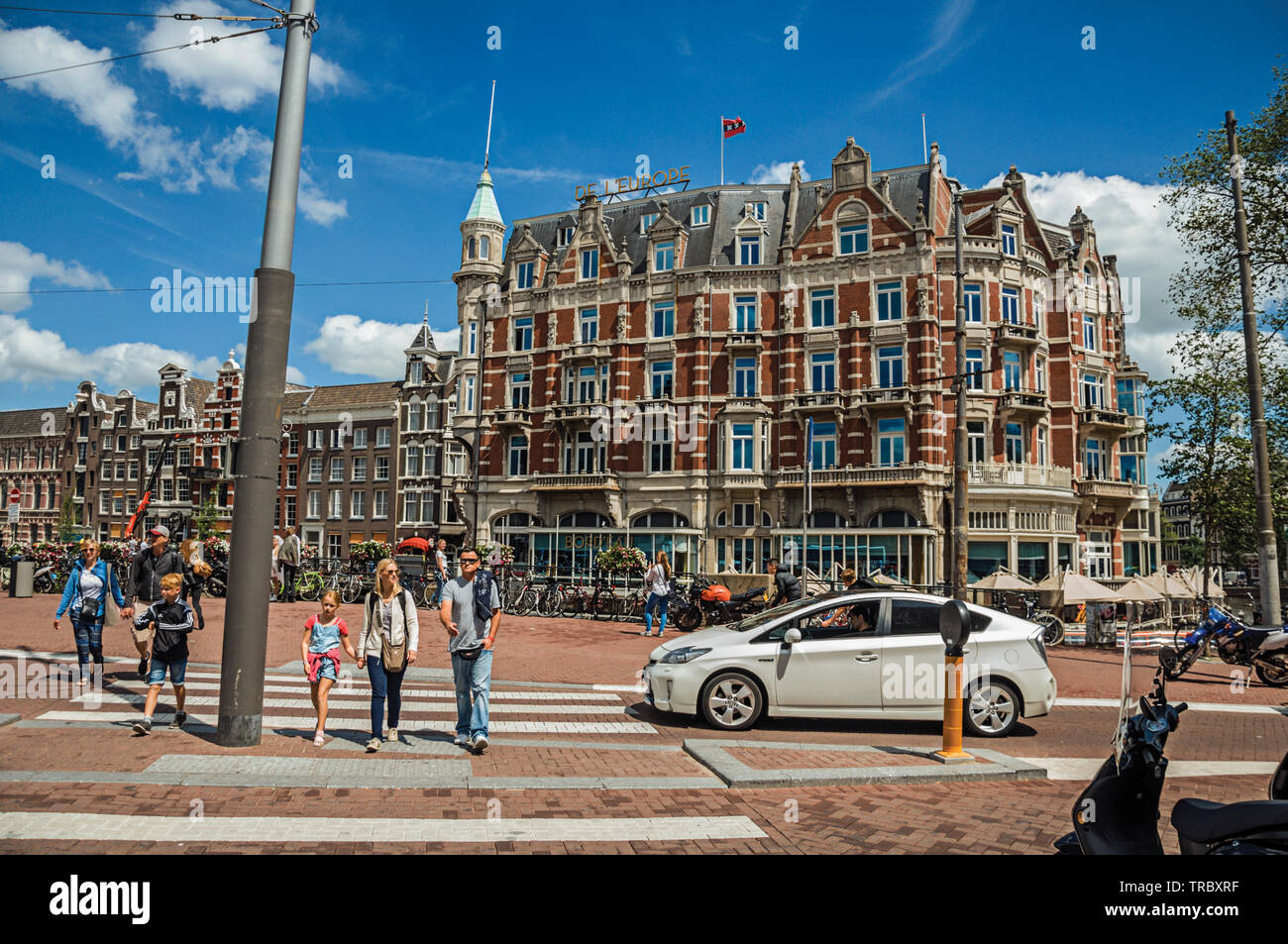 Street with typical brick buildings, people and cyclists passing by in ...