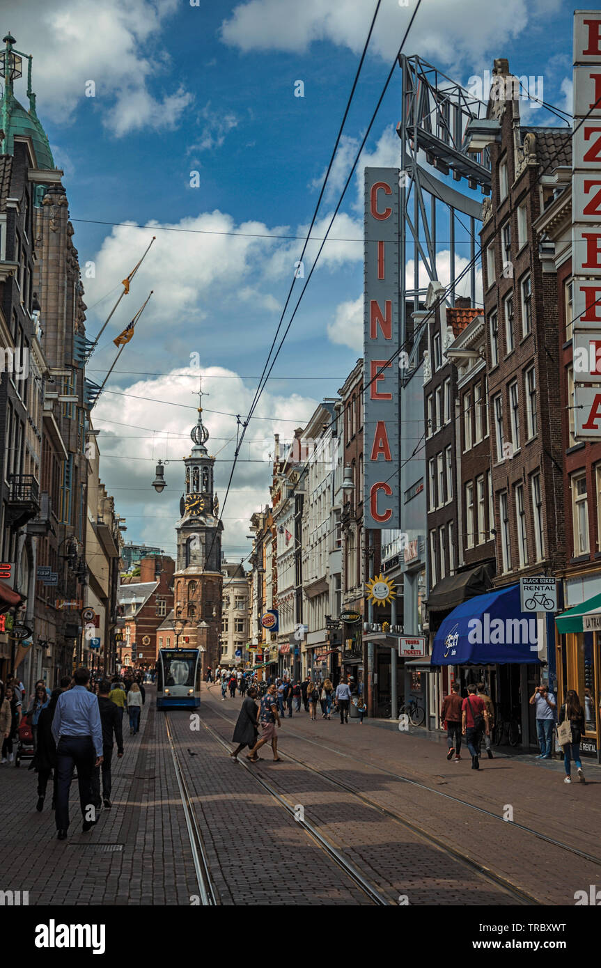 Street with brick buildings, steeple, tram and people passing by in ...