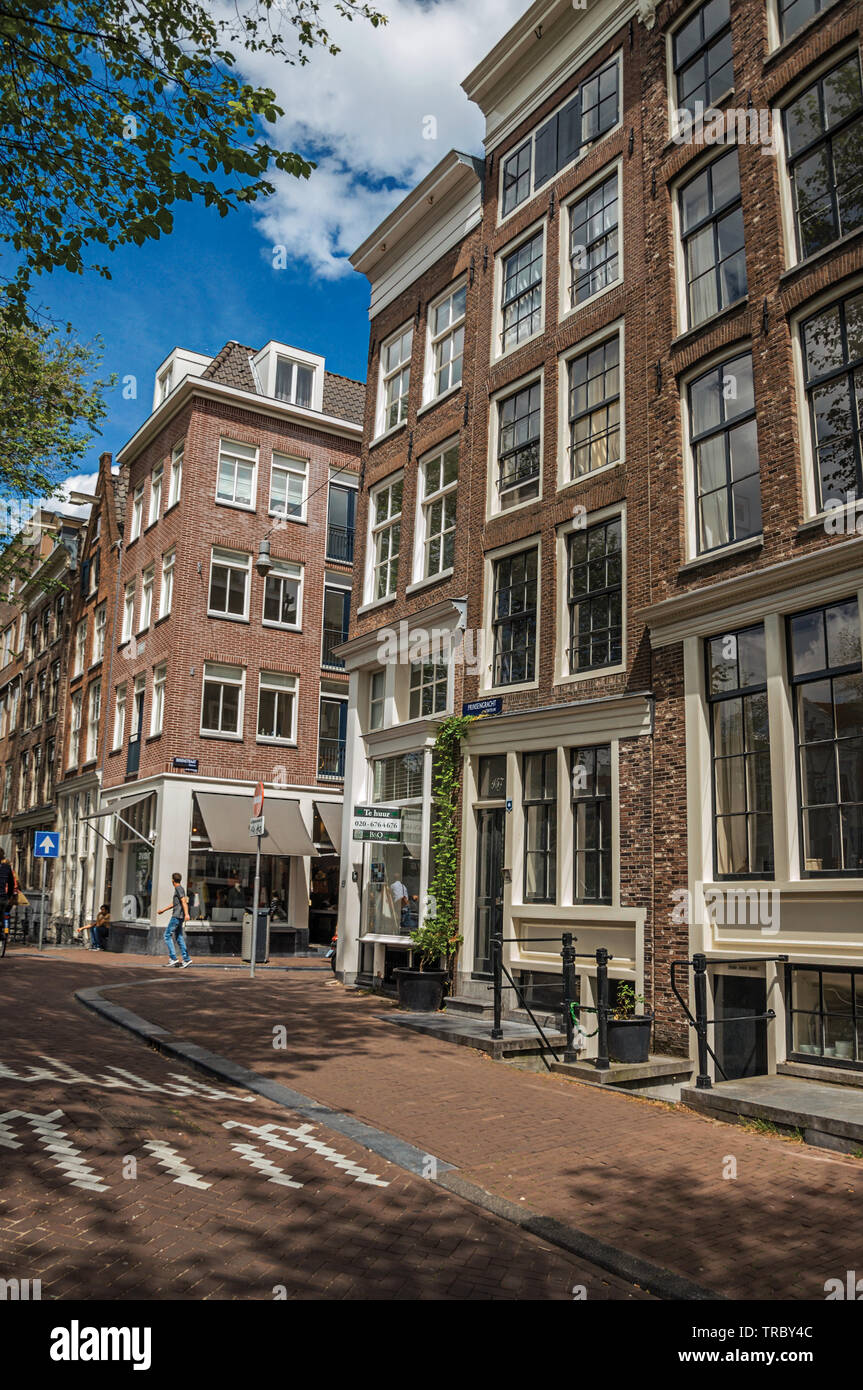 Street with old brick buildings, shops and people passing by in ...