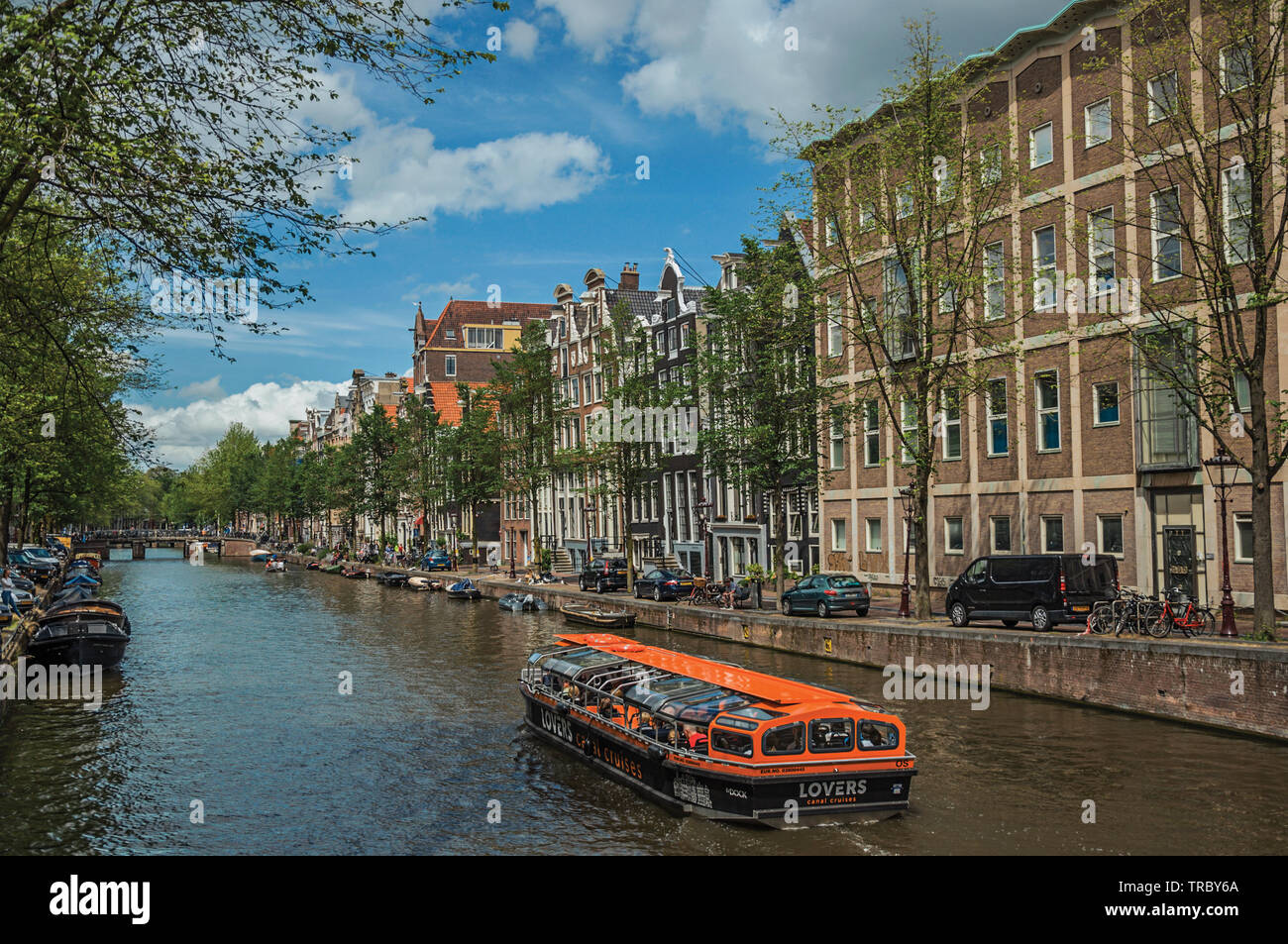 Canal with old brick buildings, boats and sunny blue sky in Amsterdam ...