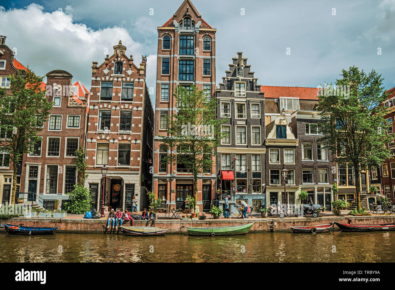 Canal with old brick buildings, boats and sunny blue sky in Amsterdam ...