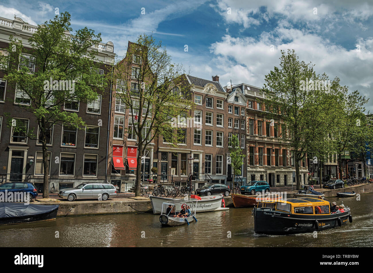 Canal with old brick buildings, boats and sunny blue sky in Amsterdam ...