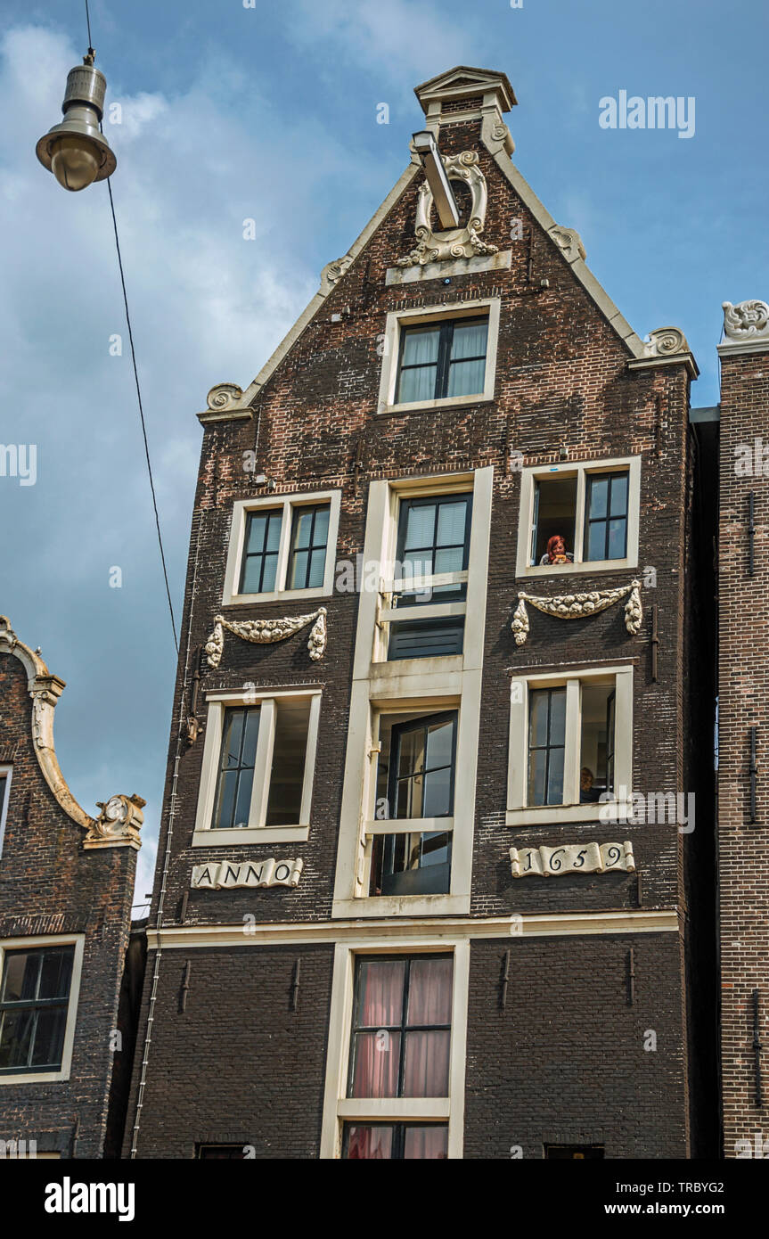 People on window of old brick building with sunny blue sky in Amsterdam ...
