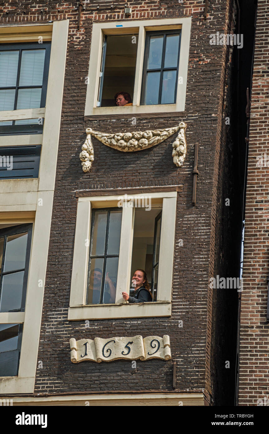 People on windows of old brick building with sunny blue sky in ...