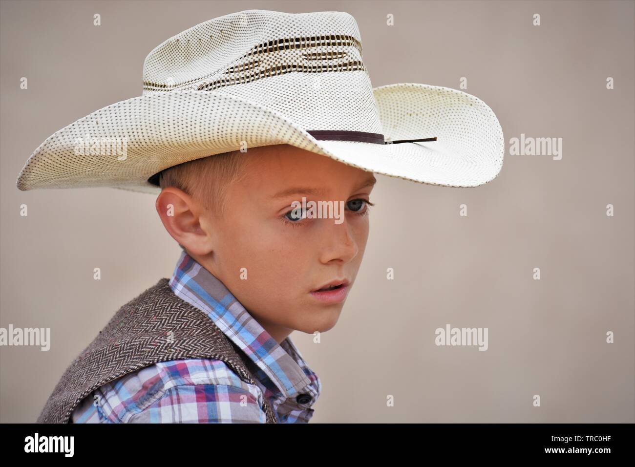 Young kid face, at rodeo parade with cowboy hat and vest with family in ...
