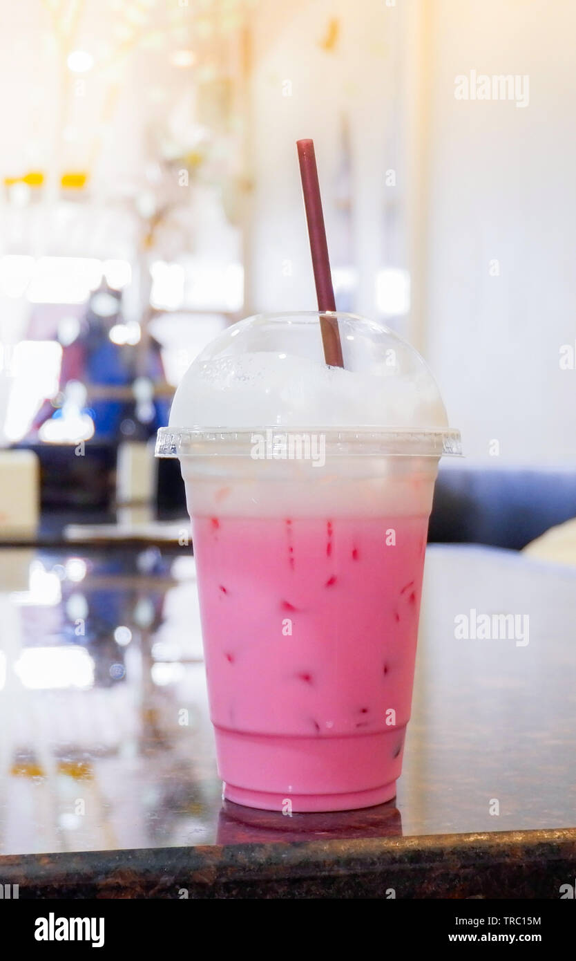 Strawberry milk pink shake iced in plastic cup and straw on table ...