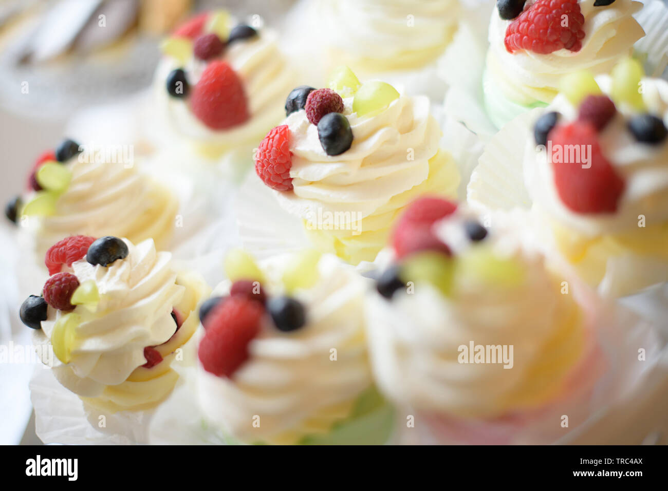 Delicious custard and berries cupcakes, assortment of sweets and cakes ...