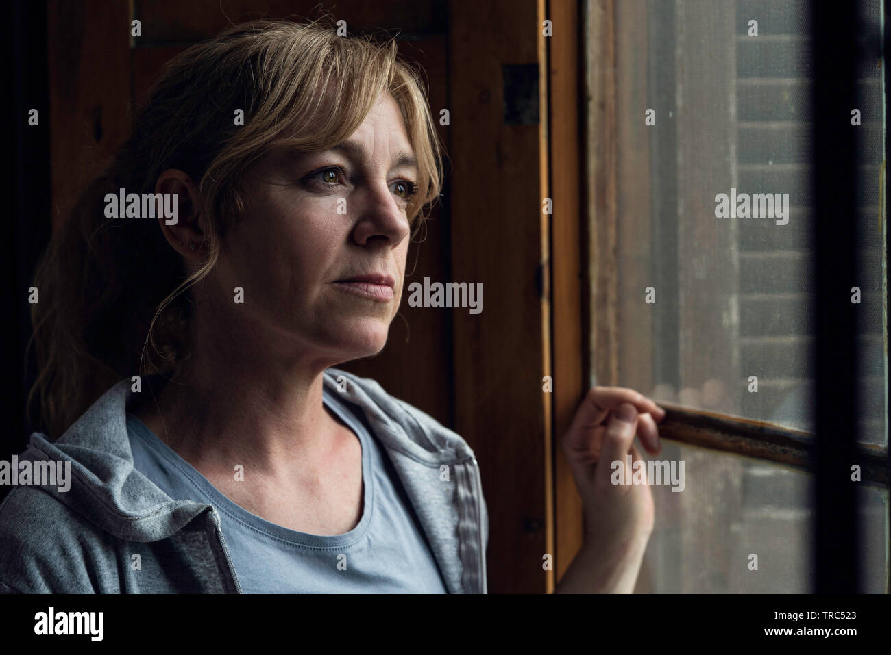 Woman looking through window Stock Photo - Alamy