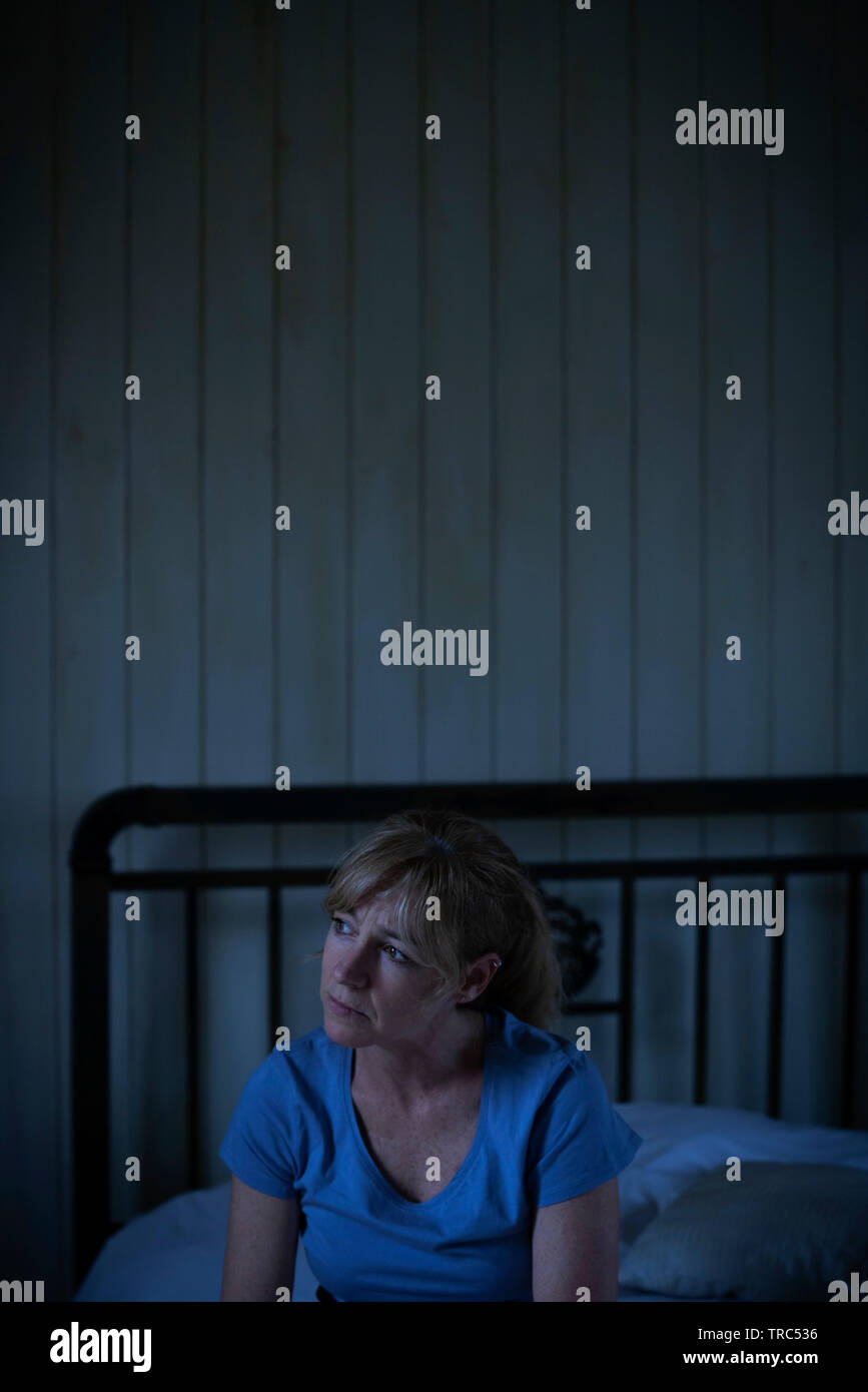 Thoughtful sad woman sitting on bed Stock Photo - Alamy