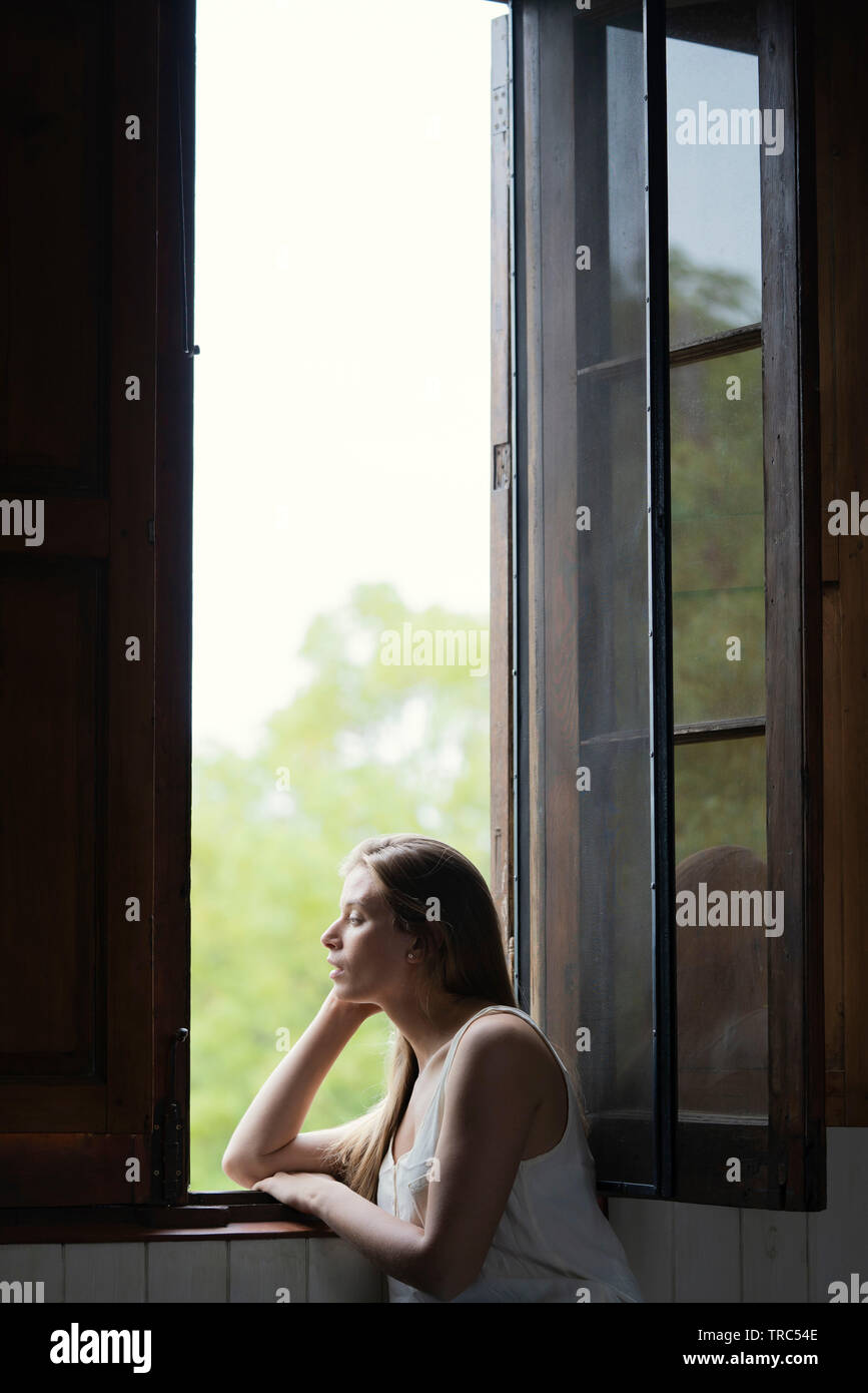 Woman looking through window Stock Photo - Alamy