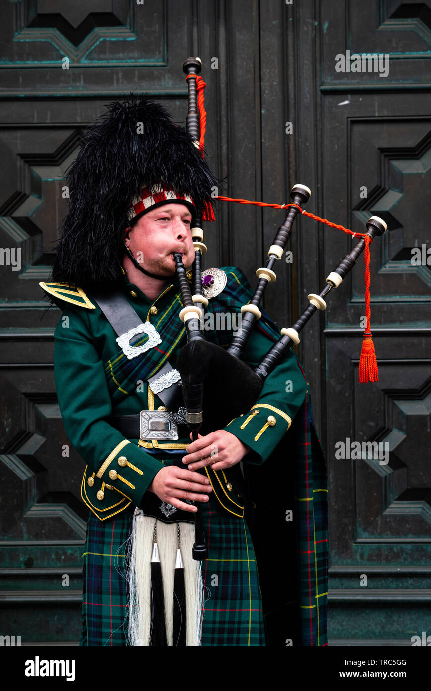 Scottish piper playing bagpipes on Royal Mile outside Edinburgh High ...