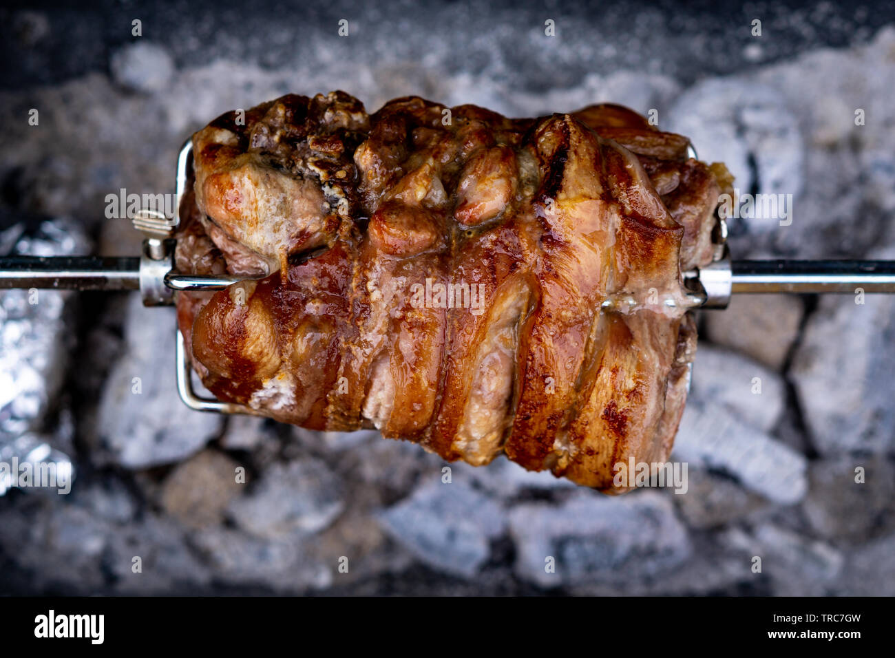 Delicious Pork shoulder slow cooked over coals on a spit rotisserie ...