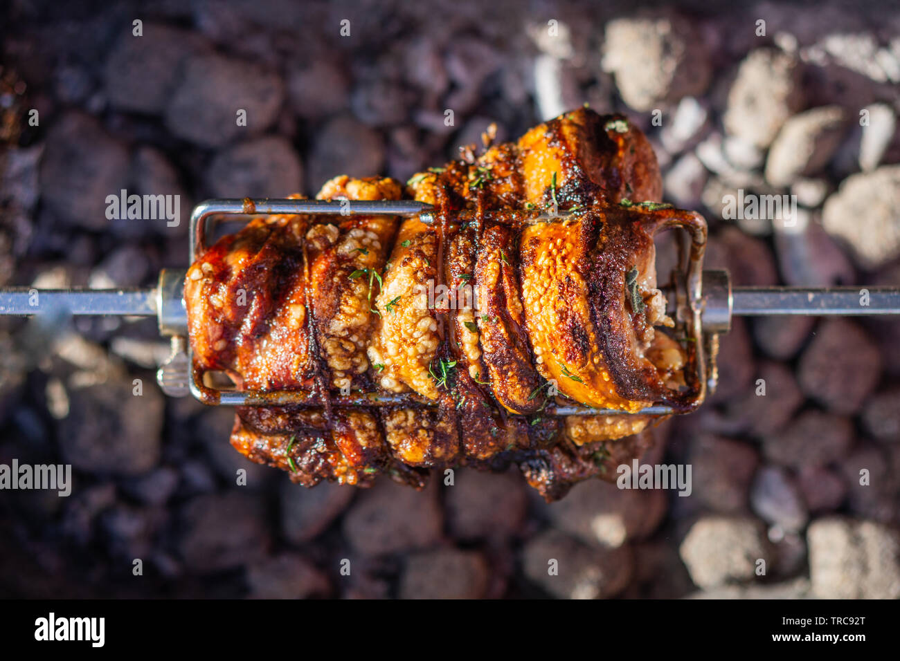 Delicious Pork shoulder slow cooked over coals on a spit rotisserie ...