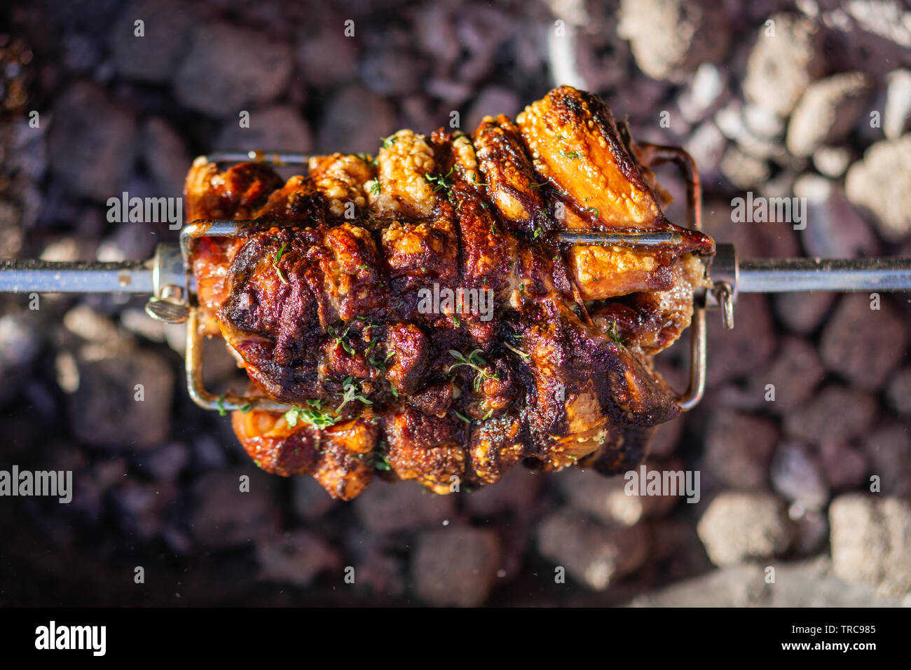 Delicious Pork shoulder slow cooked over coals on a spit rotisserie ...