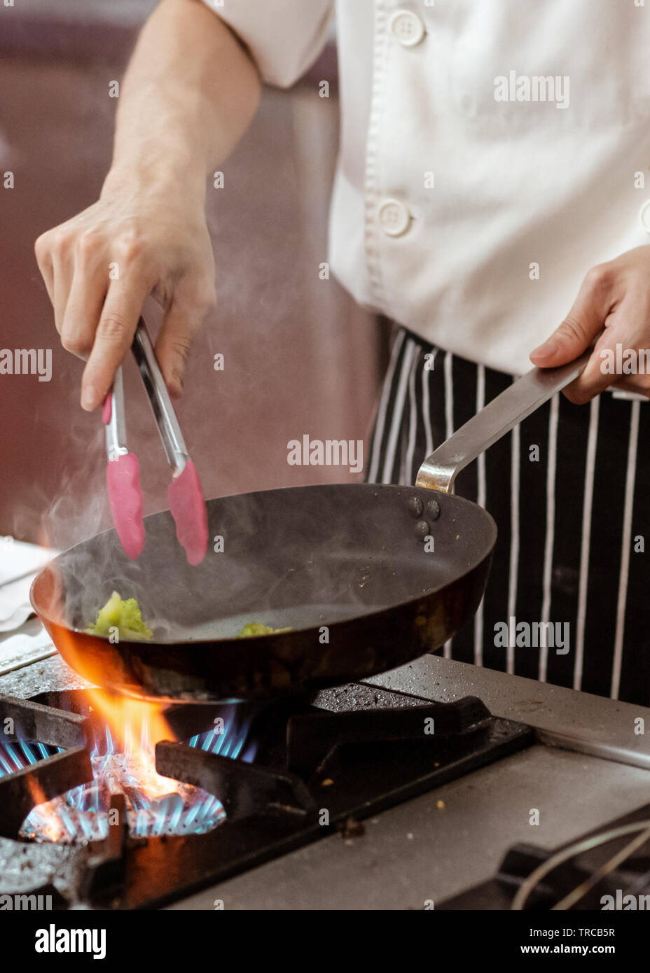Chef cooking with flame in a frying pan on a kitchen stove Stock Photo ...
