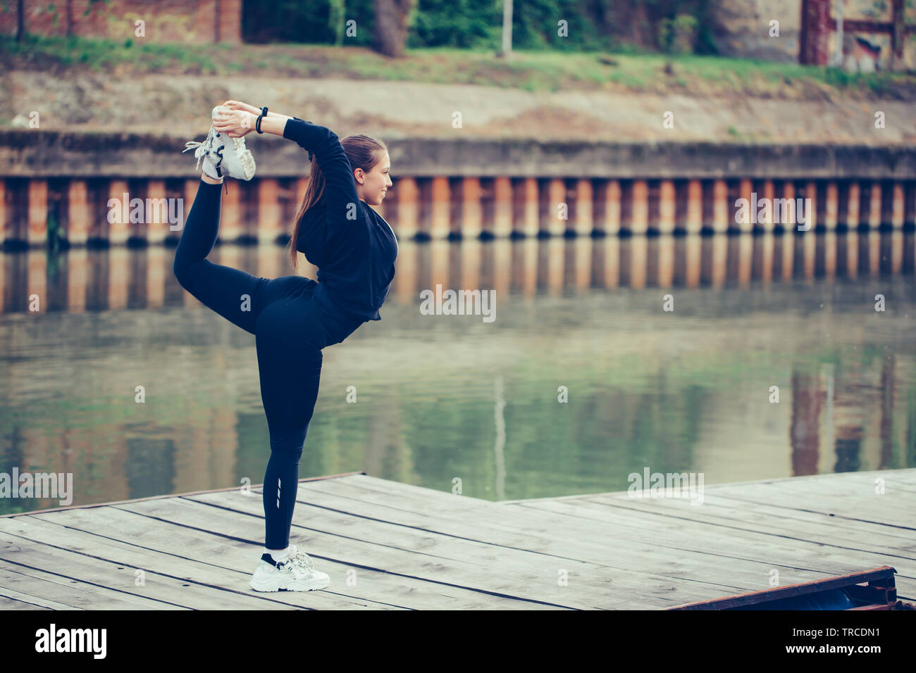 Young beautiful woman doing stretching exercises by the river Stock Photo - Alamy