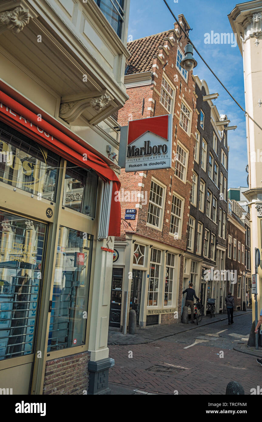Narrow street with brick buildings, shops and people in Amsterdam. City ...