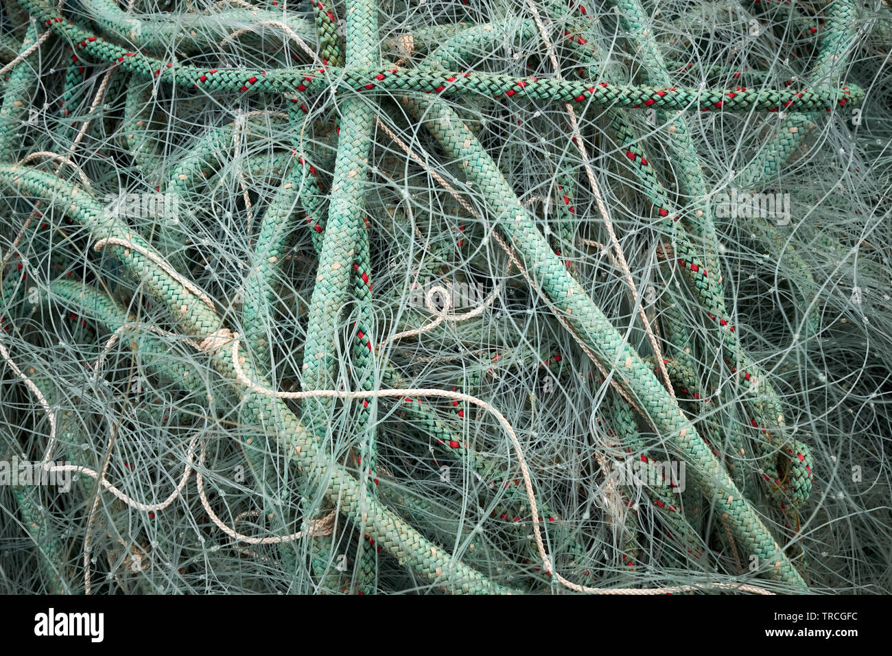 Green nylon plastic fishing nets and rope on a beach Stock Photo - Alamy