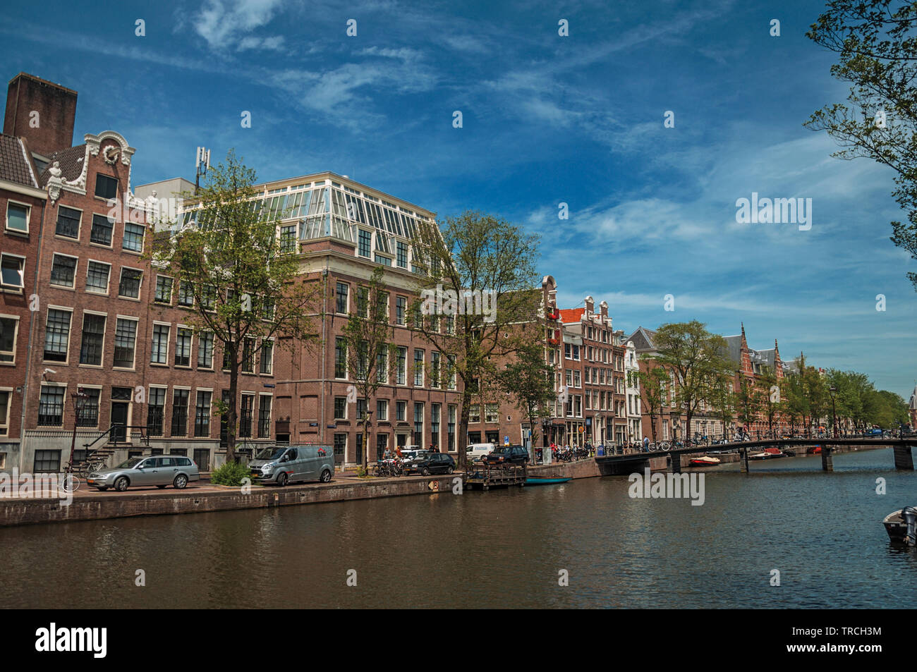 Canal with brick buildings, bridge and sunny blue sky in Amsterdam ...