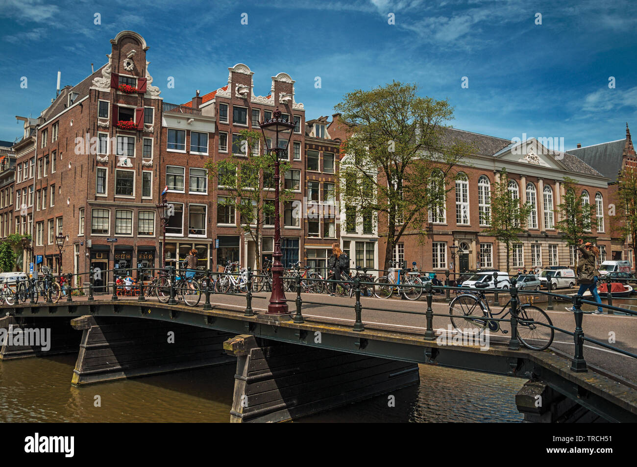 Canal with brick buildings, bicycles on bridge and sunny blue sky in ...