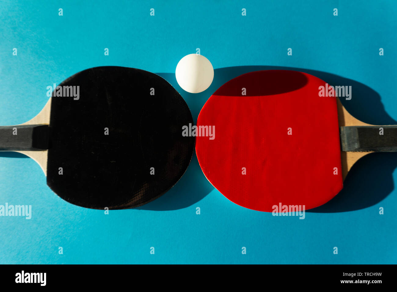A close up of table tennis bats and ball on a blue background with copy ...