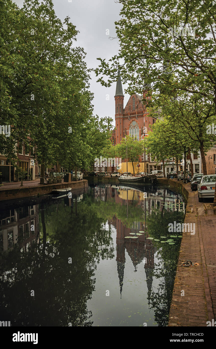 Canal with trees along, brick church and cloudy sky, in the city center ...