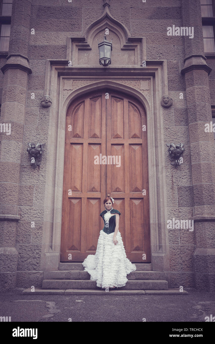 A woman like a princess in an vintage dress beside old castle ...