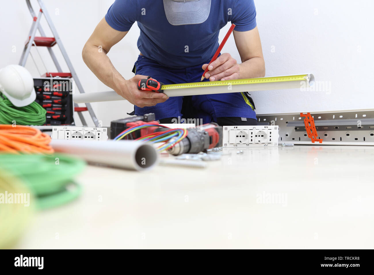 electrician at work with meter and pencil in hands measures the plastic ...