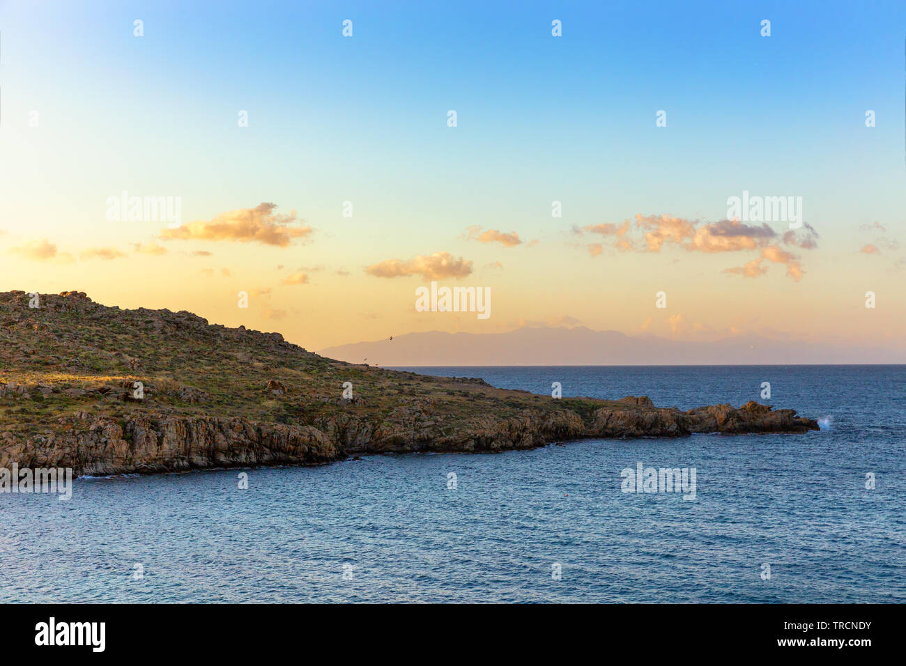 Colorful sunrise over a rocky shoreline in Mykonos, Greece Stock Photo ...