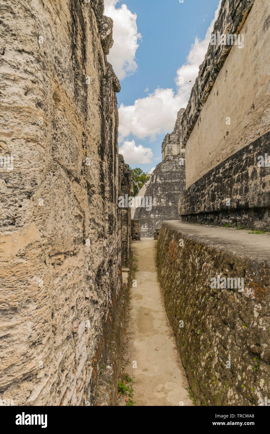 Looking down a narrow passageway of ancient ruins, with a sliver view ...