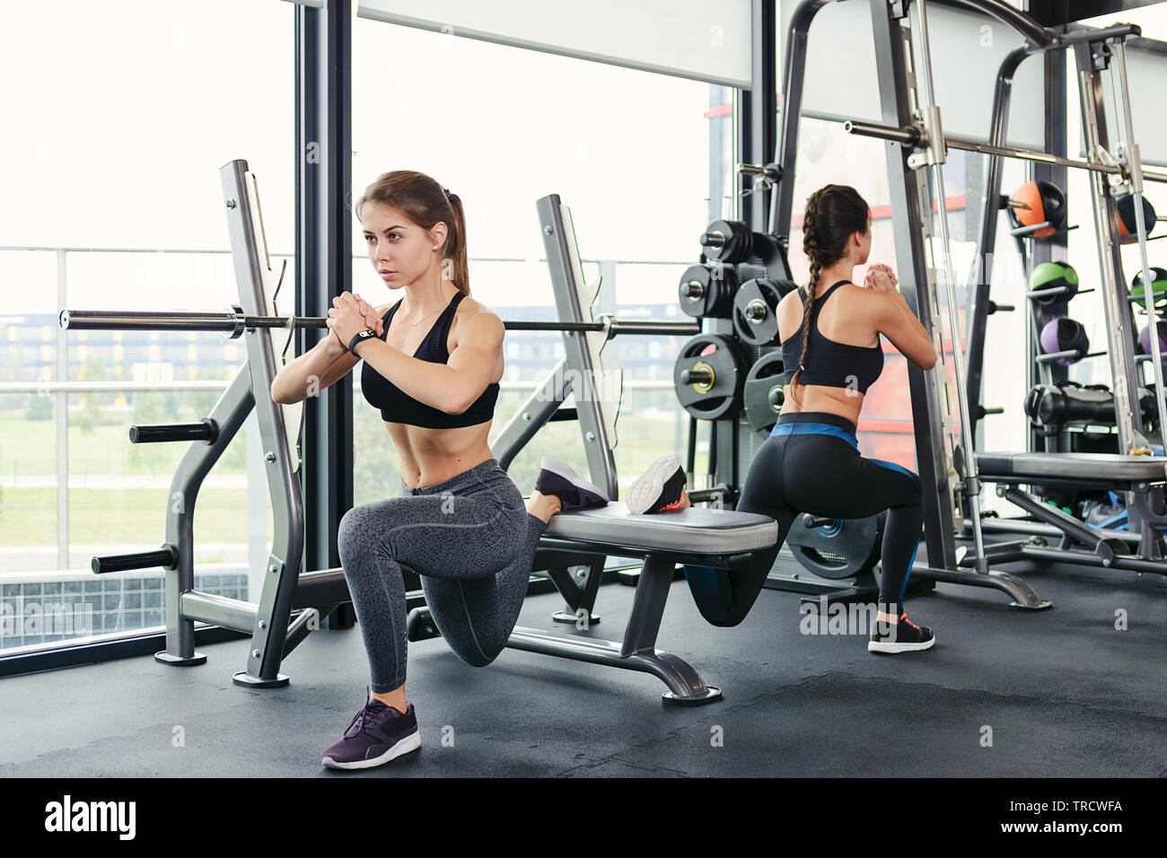Two cute athletic girls have a hard workout at the gym, doing weight ...