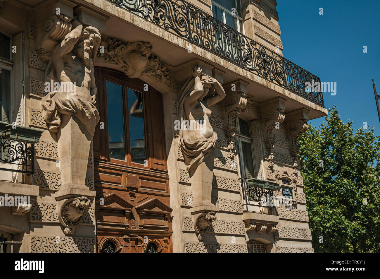 Wood gate and sculptures in human form that support terrace of building ...