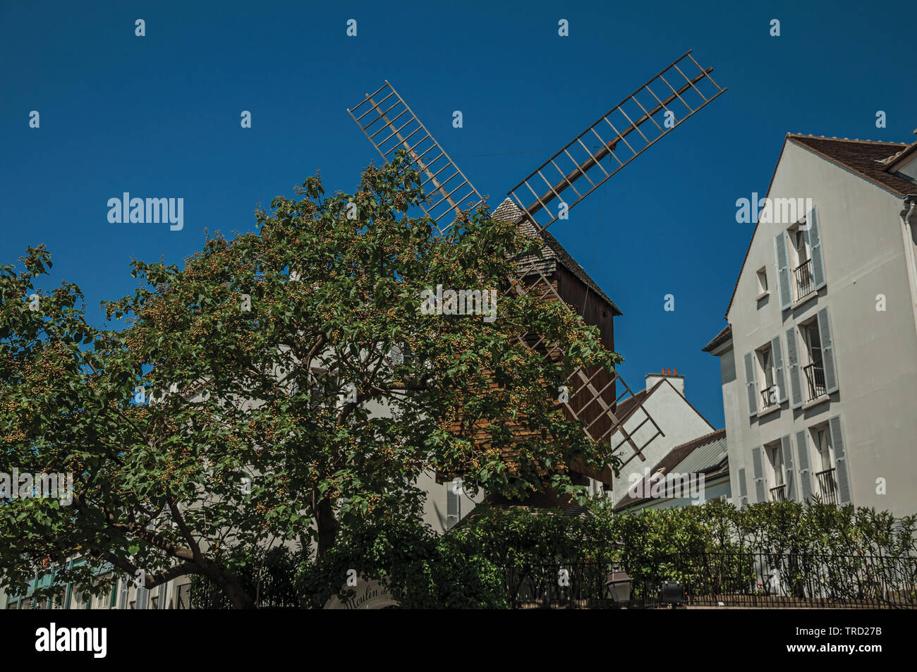 Old windmill and buildings under sunny blue sky in the Montmartre ...