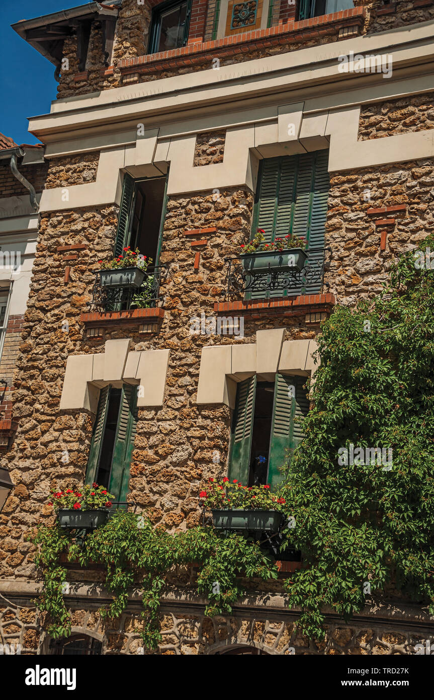 Old brick building with flowers on windows and sunny day at Montmartre ...