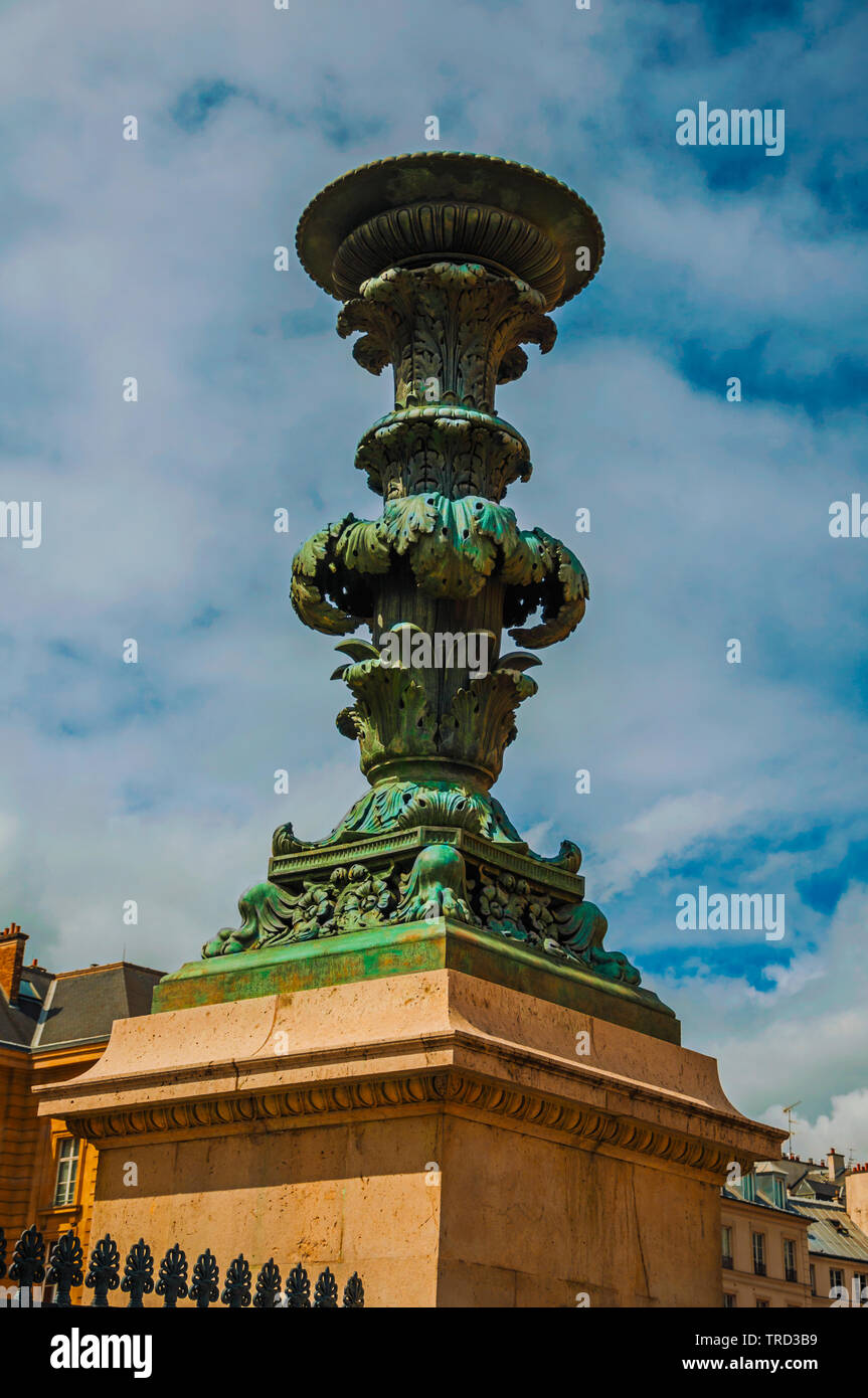Bronze decoration on marble pedestal with cloudy sky in Paris. One of ...