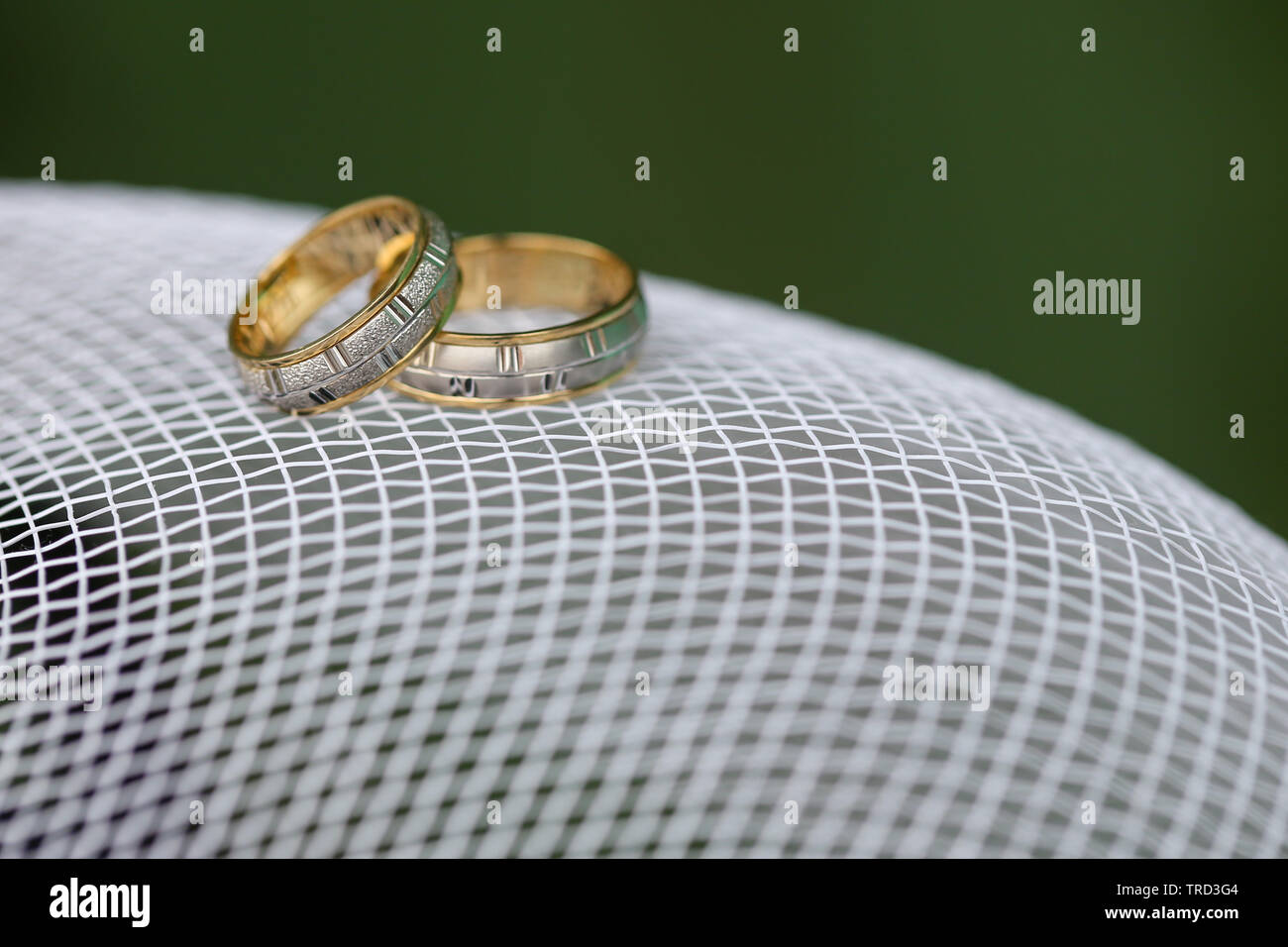 Golden wedding rings on the white mesh with green background Stock ...