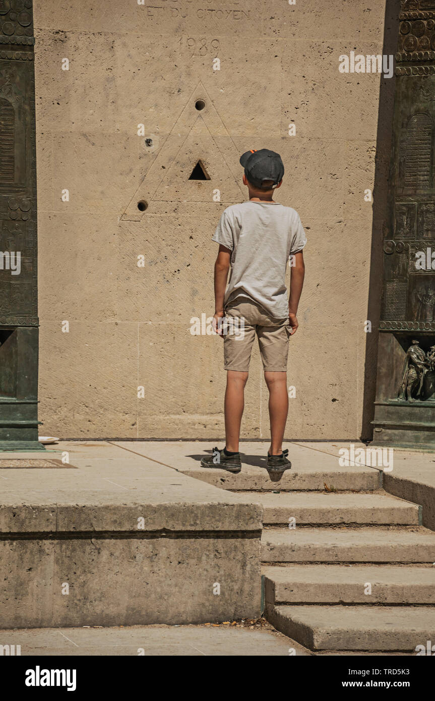 Boy staring at granite holes on the Human Rights Monument in Paris. One ...