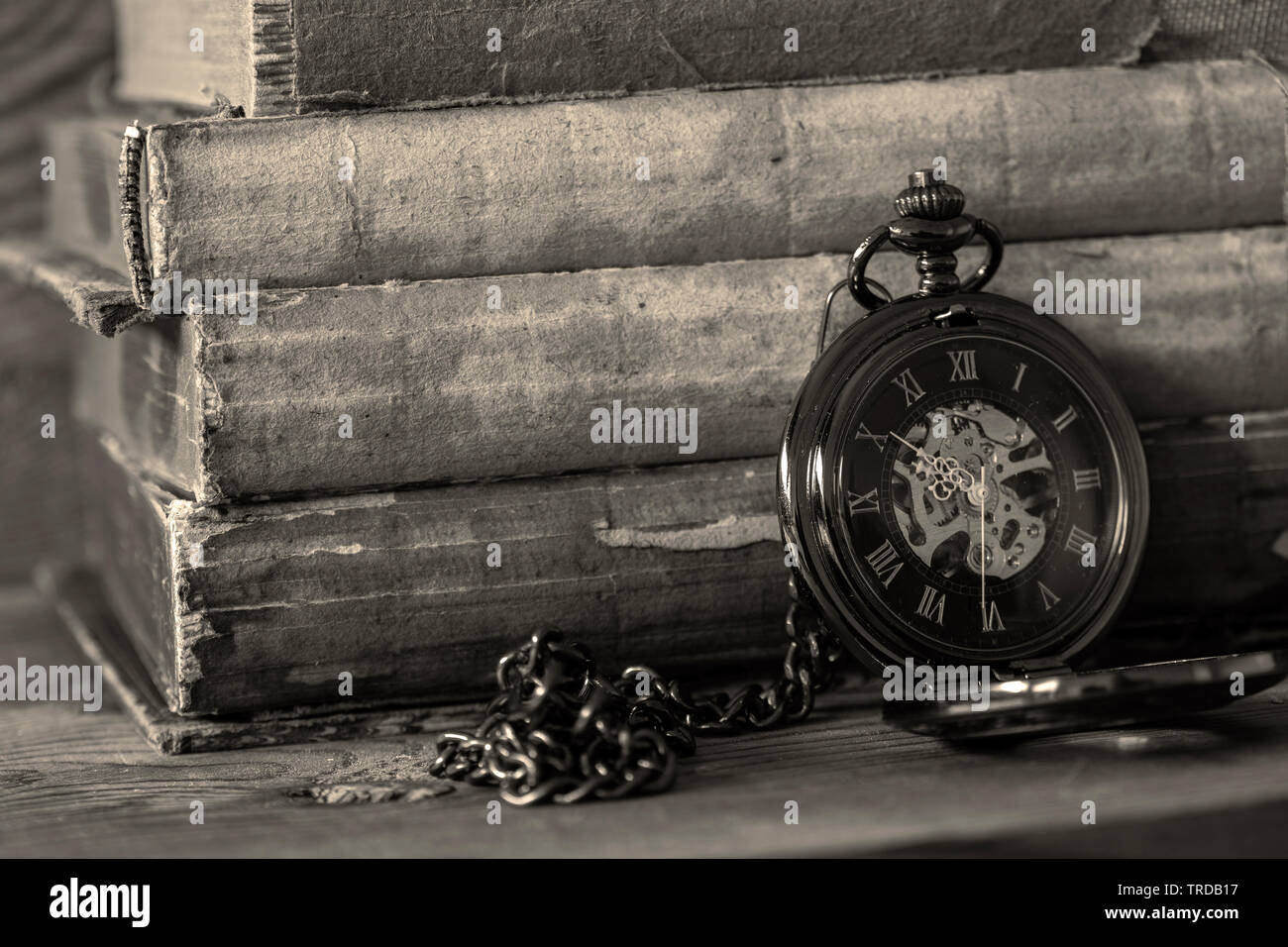 Antique pocket fob watch with a chain leaning on a stack of old books ...