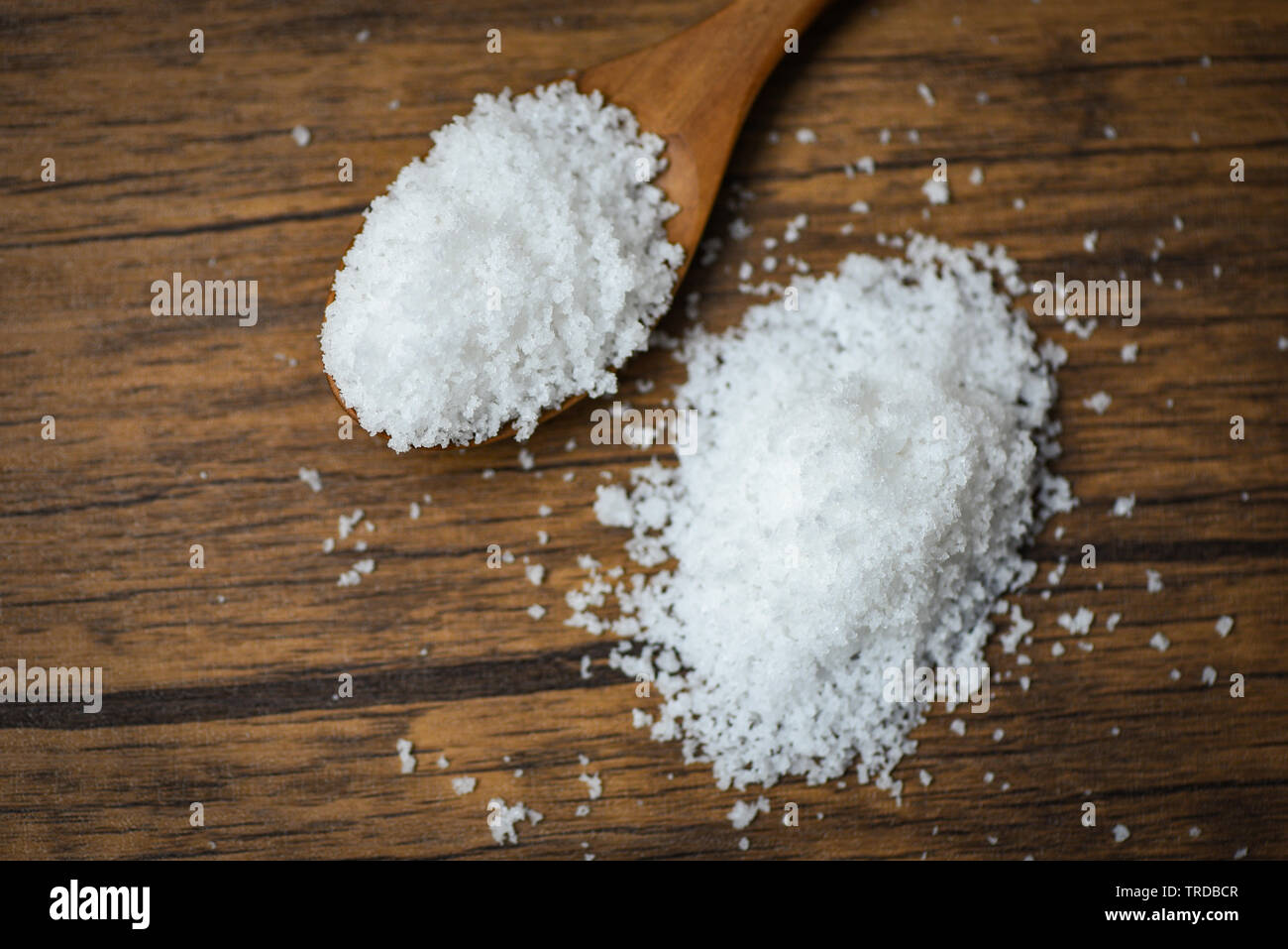 Salt in wooden spoon and heap of white salt on wood background Stock ...