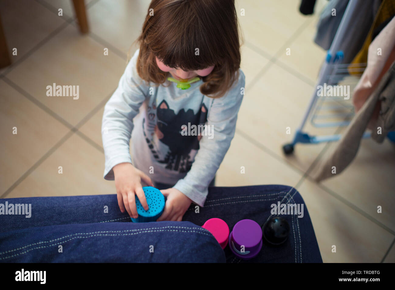 toddler baby girl with pacificator, playing at home with colorful vases ...