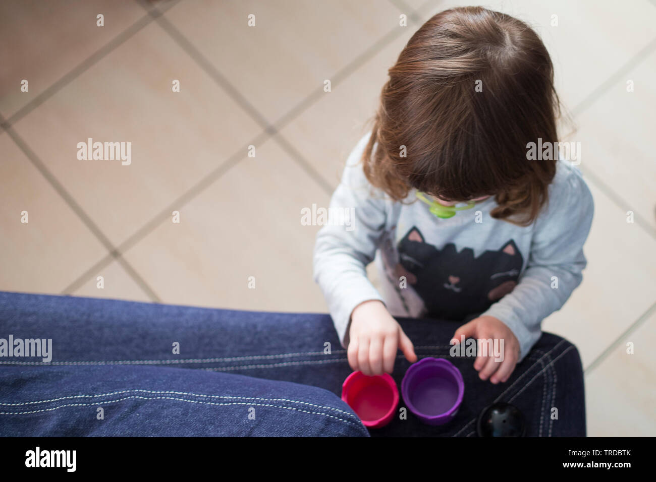 toddler baby girl with pacificator, playing at home with colorful vases ...