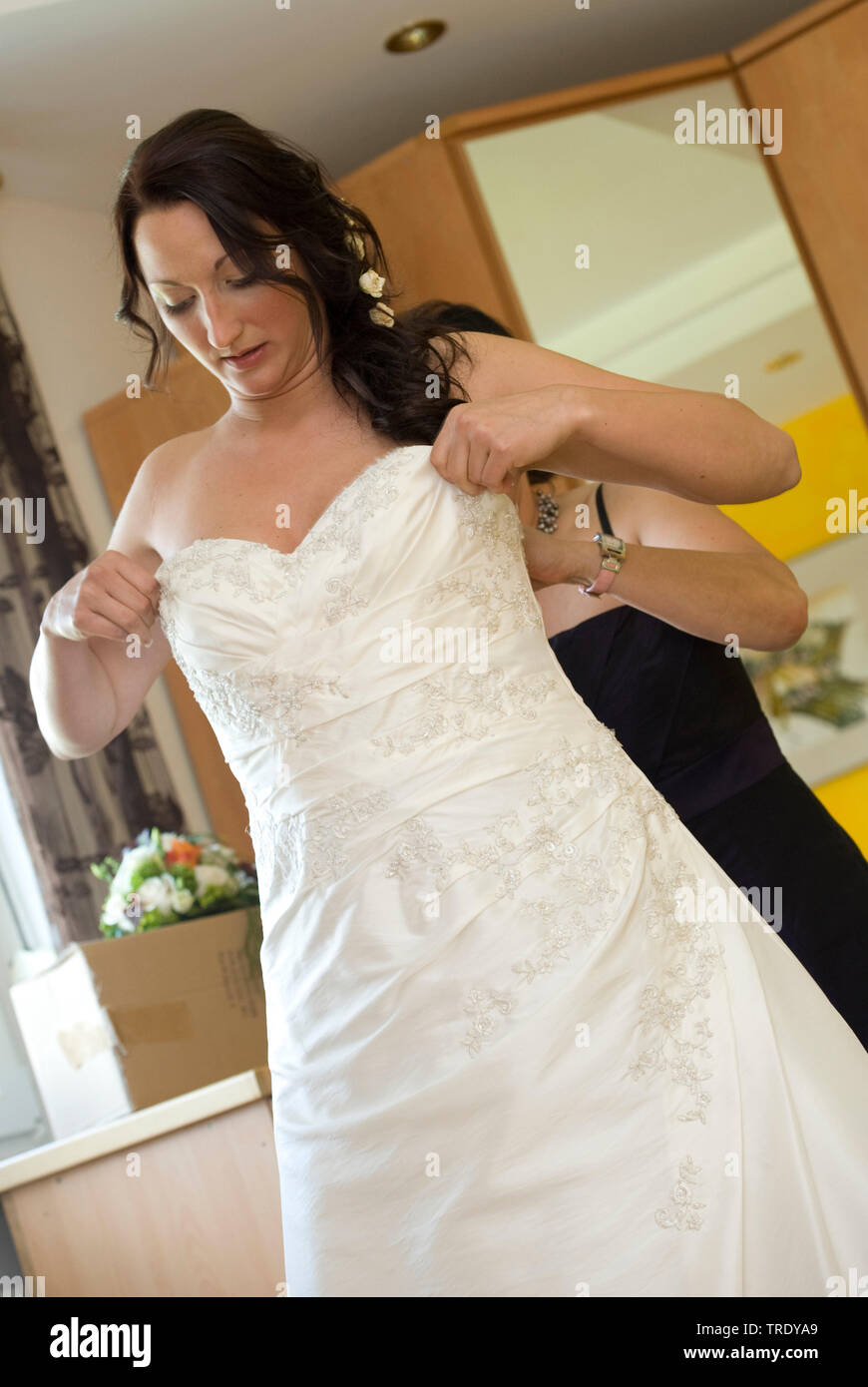 Portrait of a woman getting dressed in a bridal dress Stock Photo - Alamy